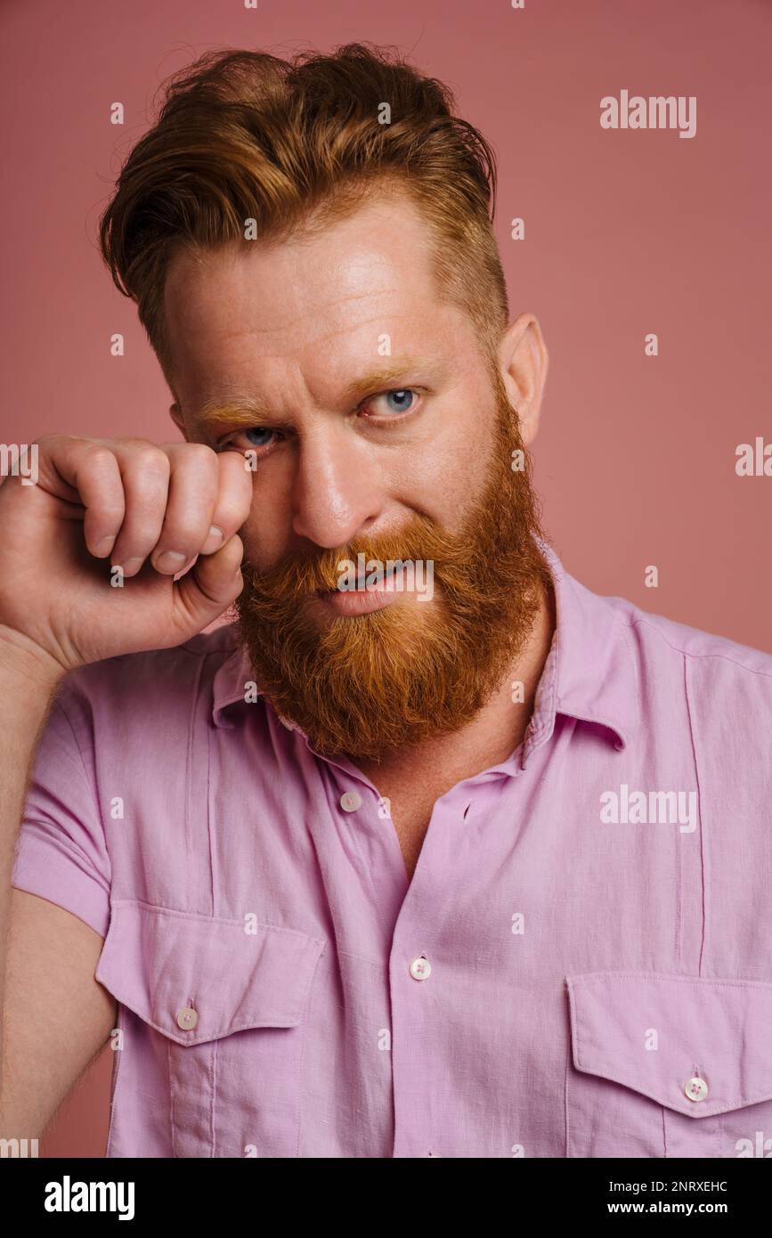 Ginger white man with beard crying while wiping his tears isolated over ...