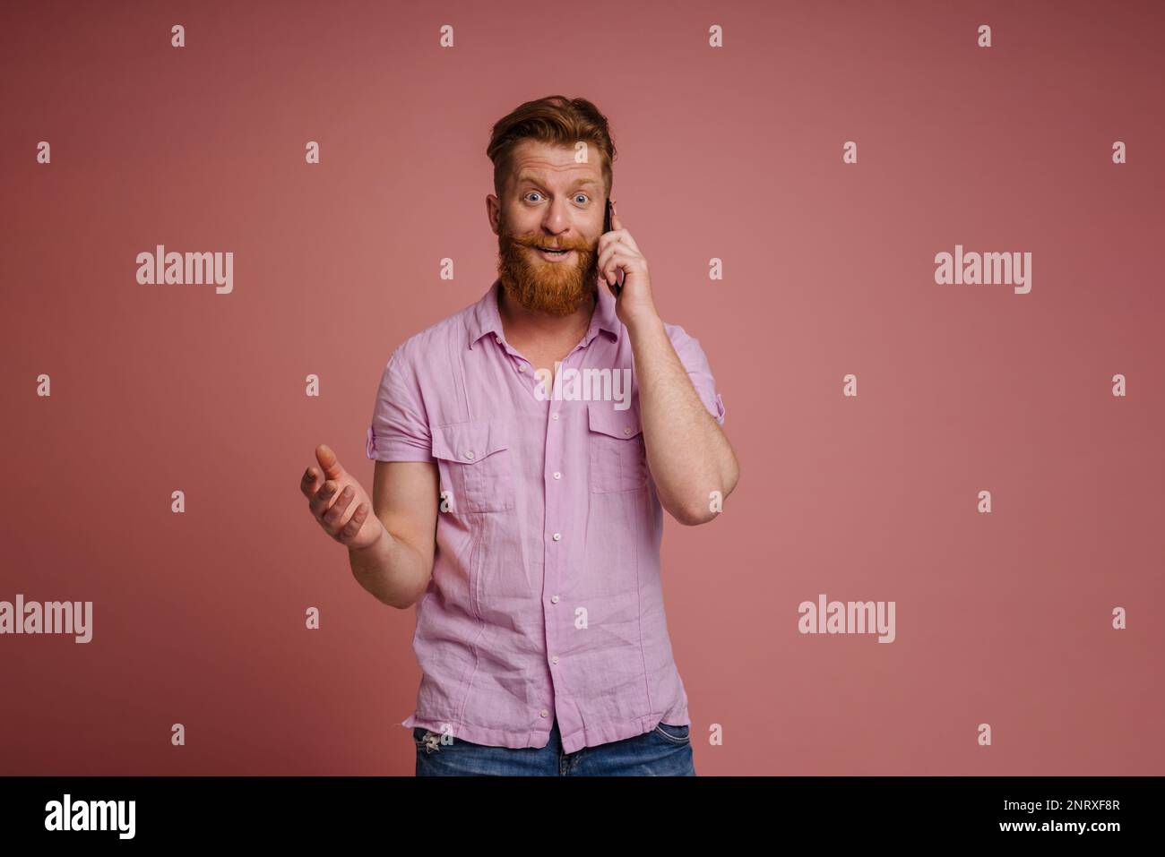 Ginger white man expressing surprise and talking on mobile phone ...