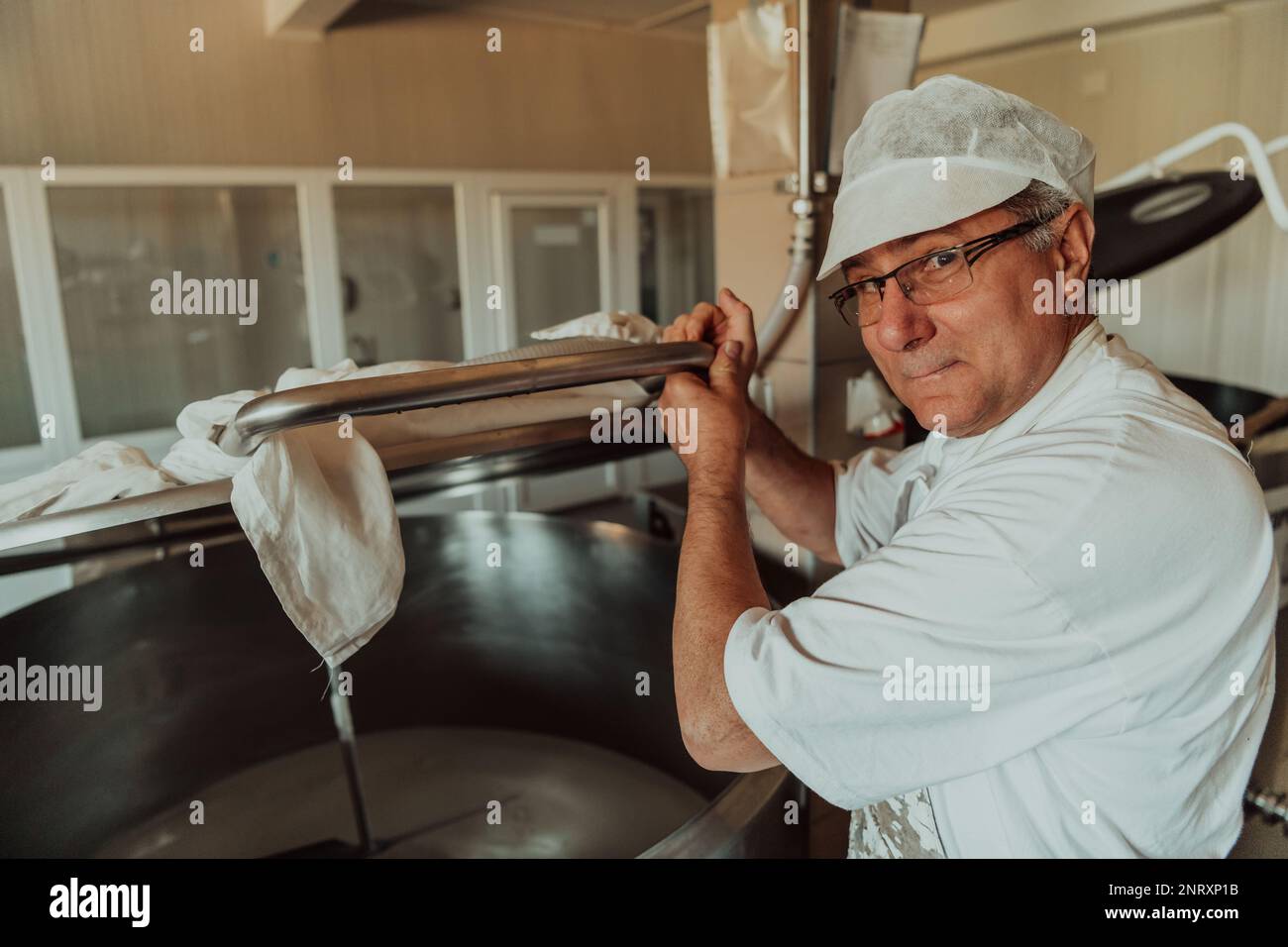 Man mixing milk in the stainless tank during the fermentation process ...