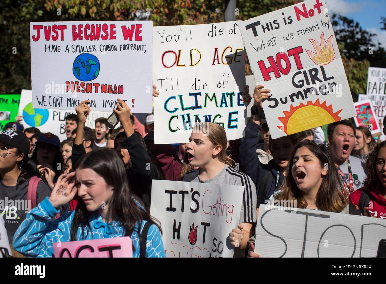 People hold signs as thousands gather outside Vancouver City Hall ...