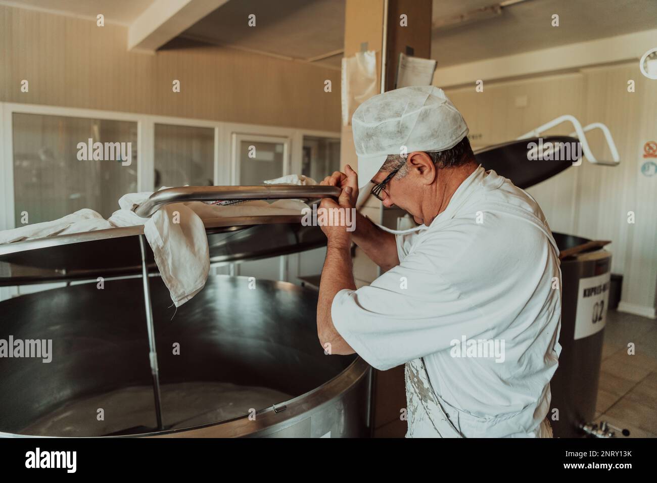 Man mixing milk in the stainless tank during the fermentation process ...