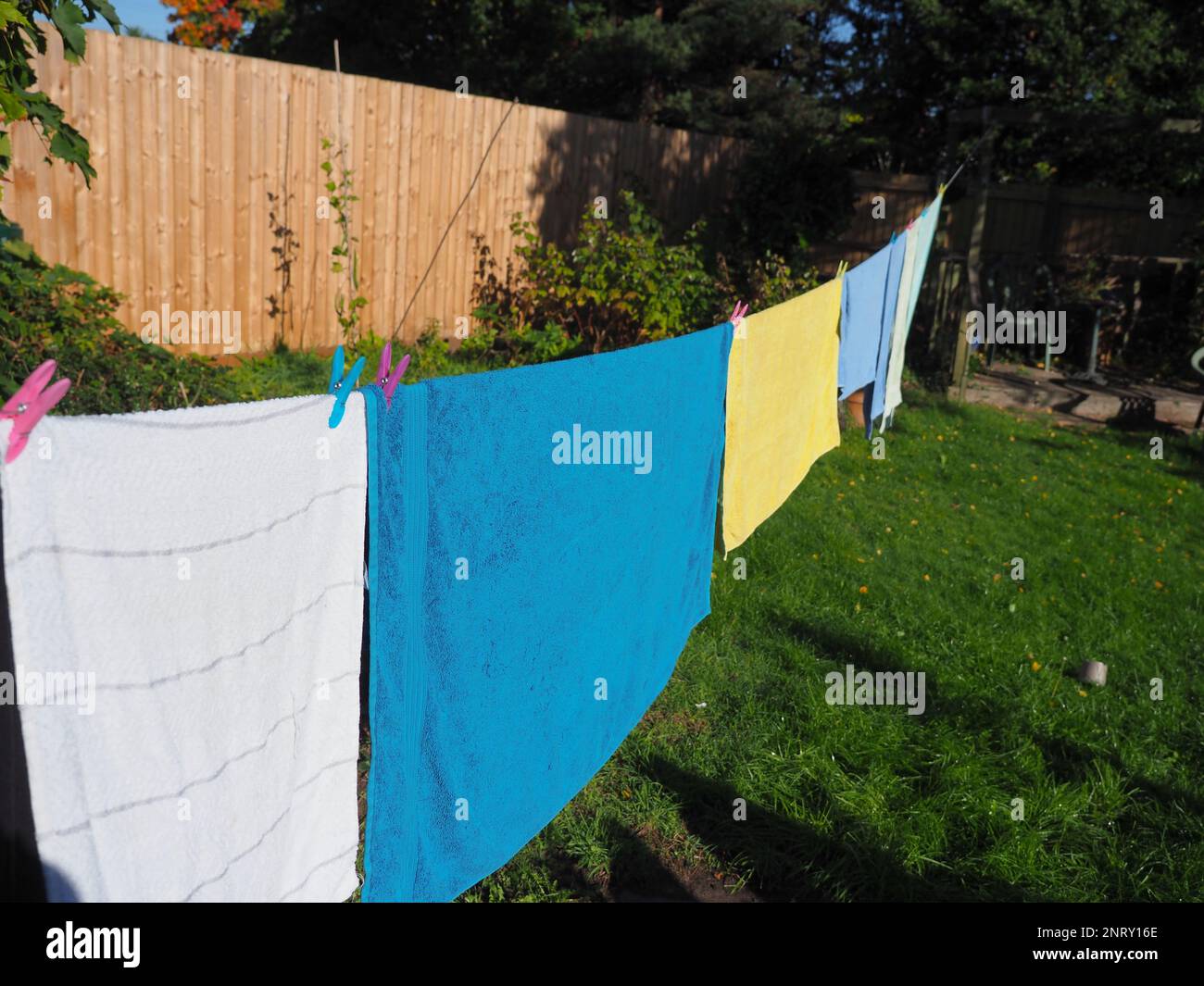 Some colourful towels hanging on a washing line in a back garden in the ...