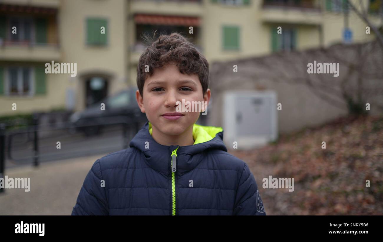 Portrait of a young boy walking forward toward camera outside wearing ...