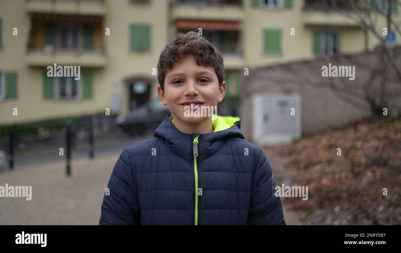 Portrait of a young boy walking forward toward camera outside wearing ...