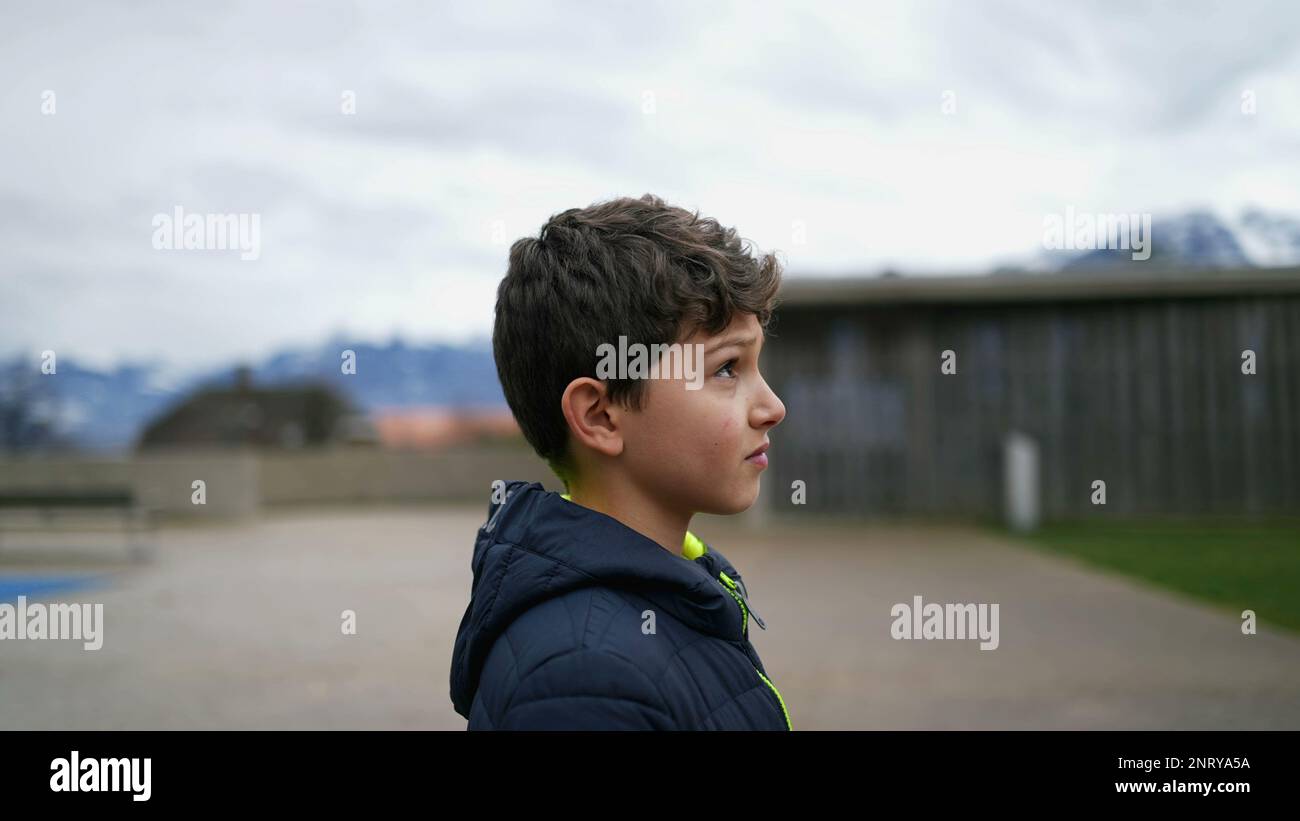 One contemplative young boy looking up at sky. Handsome child standing ...