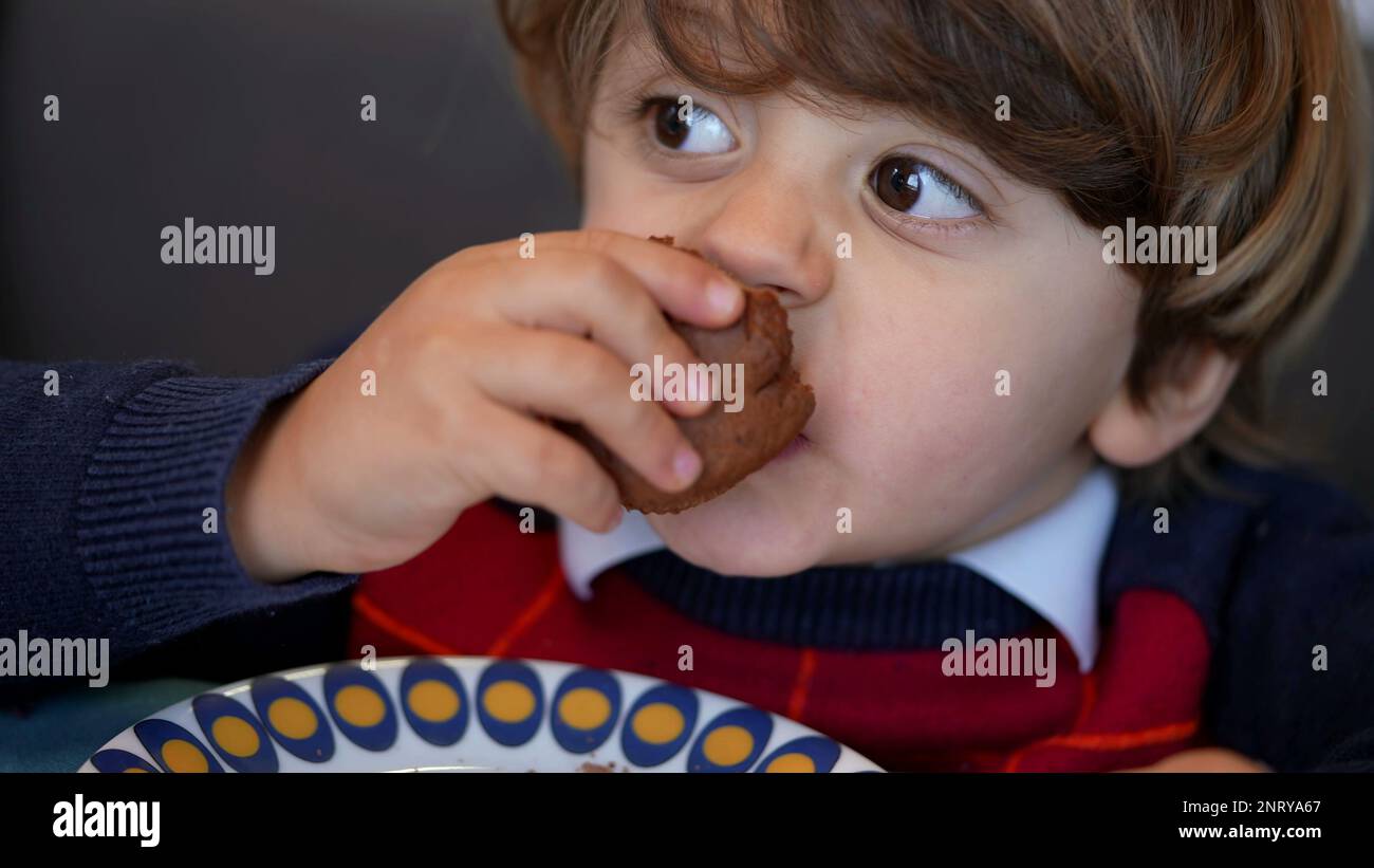 One cute small boy eating muffin. Child snacking Stock Photo - Alamy