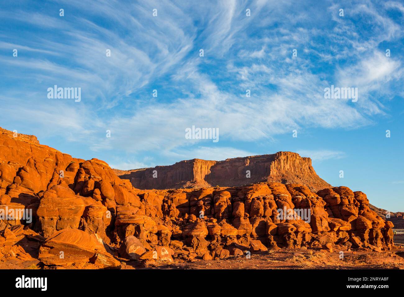 Swirling cirrus horsetail clouds over striped Cutler sandstone with ...