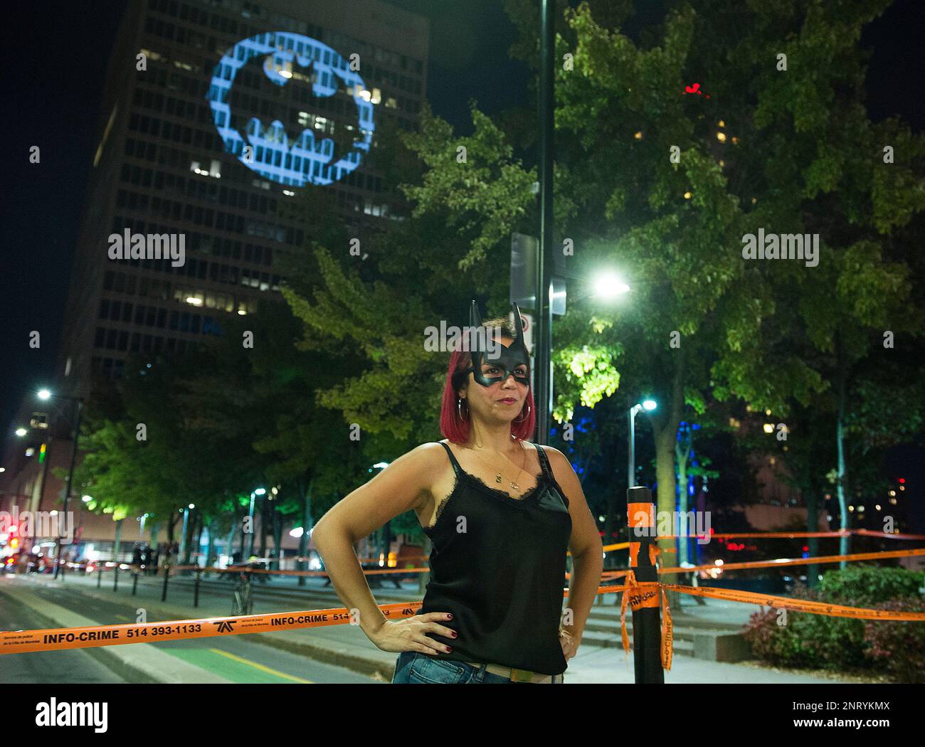 A woman poses for a photo beneath a Batman signal projected onto a ...