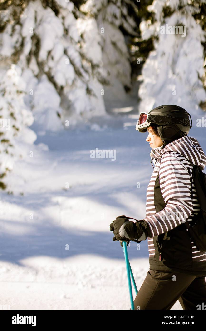 A single young female enjoys a sunny winter day of skiing, dressed in ...