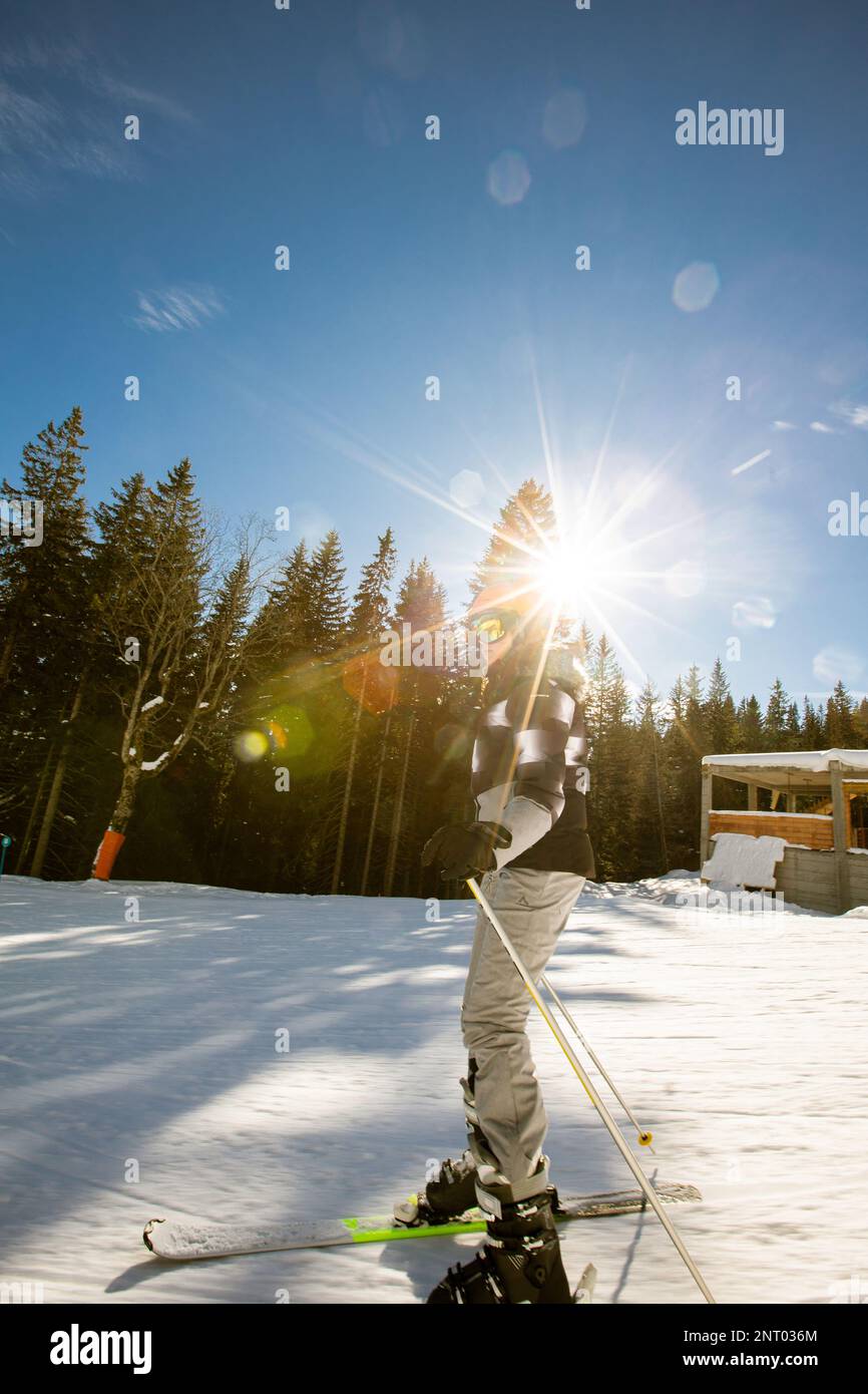 A single girl enjoys a sunny winter day of skiing, dressed in full snow ...