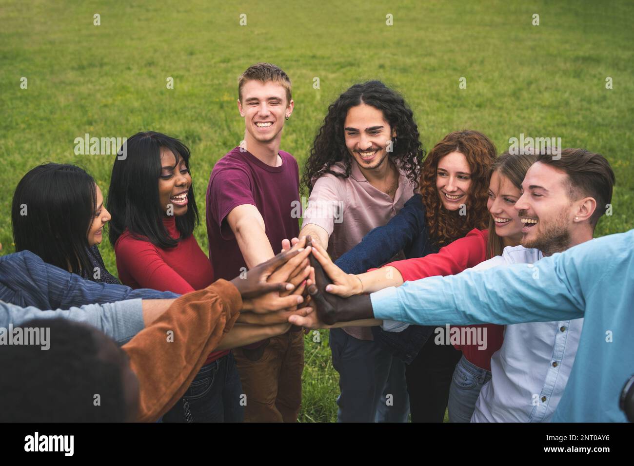 Top-down view of a multiracial group of young friends joyfully joining hands in a high five ...