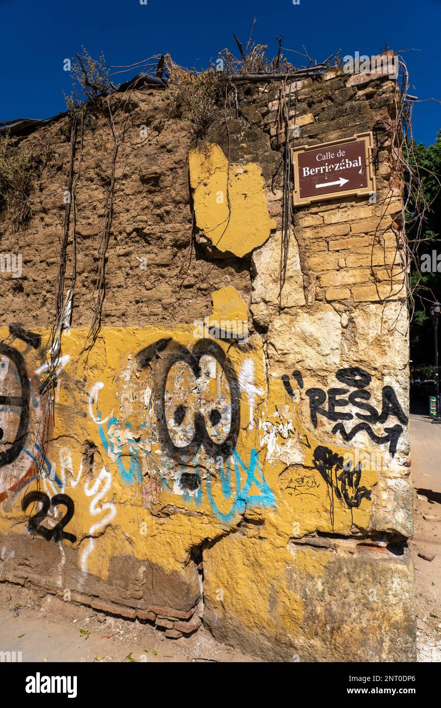 Graffitti on the severely deteriorated adobe and stone wall of an old ...