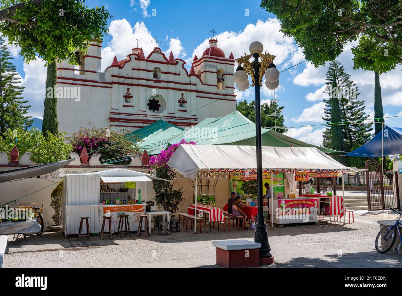 People eat in outdoor food booths on the central plaza in front of the ...