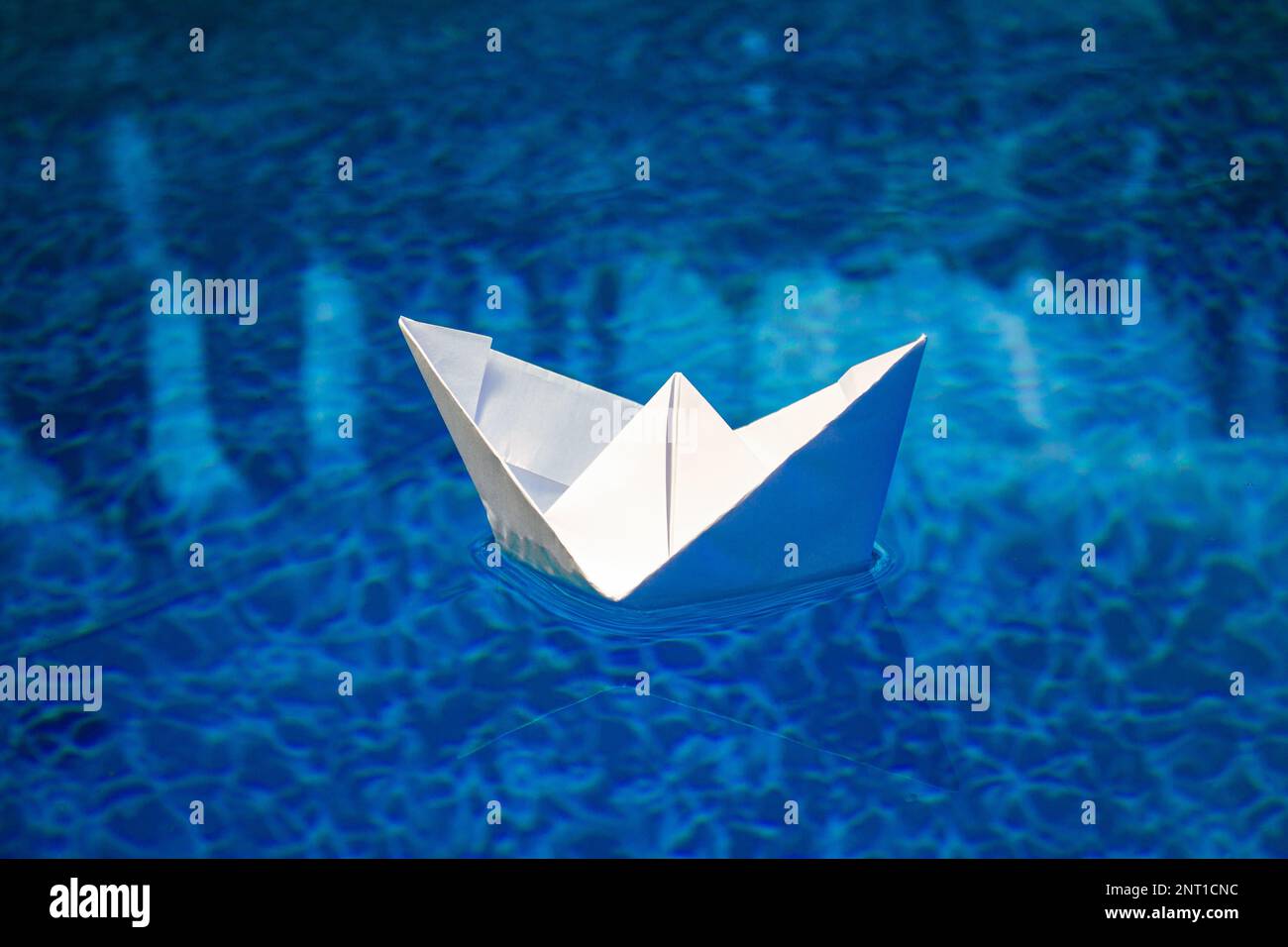 Folded paper boat floating in water Stock Photo - Alamy