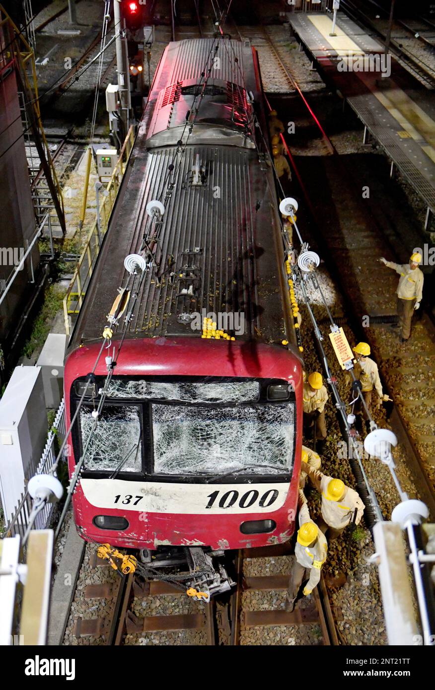 Workers push a train of KeikyuLine between Kanagawa Shinmachi Station ...