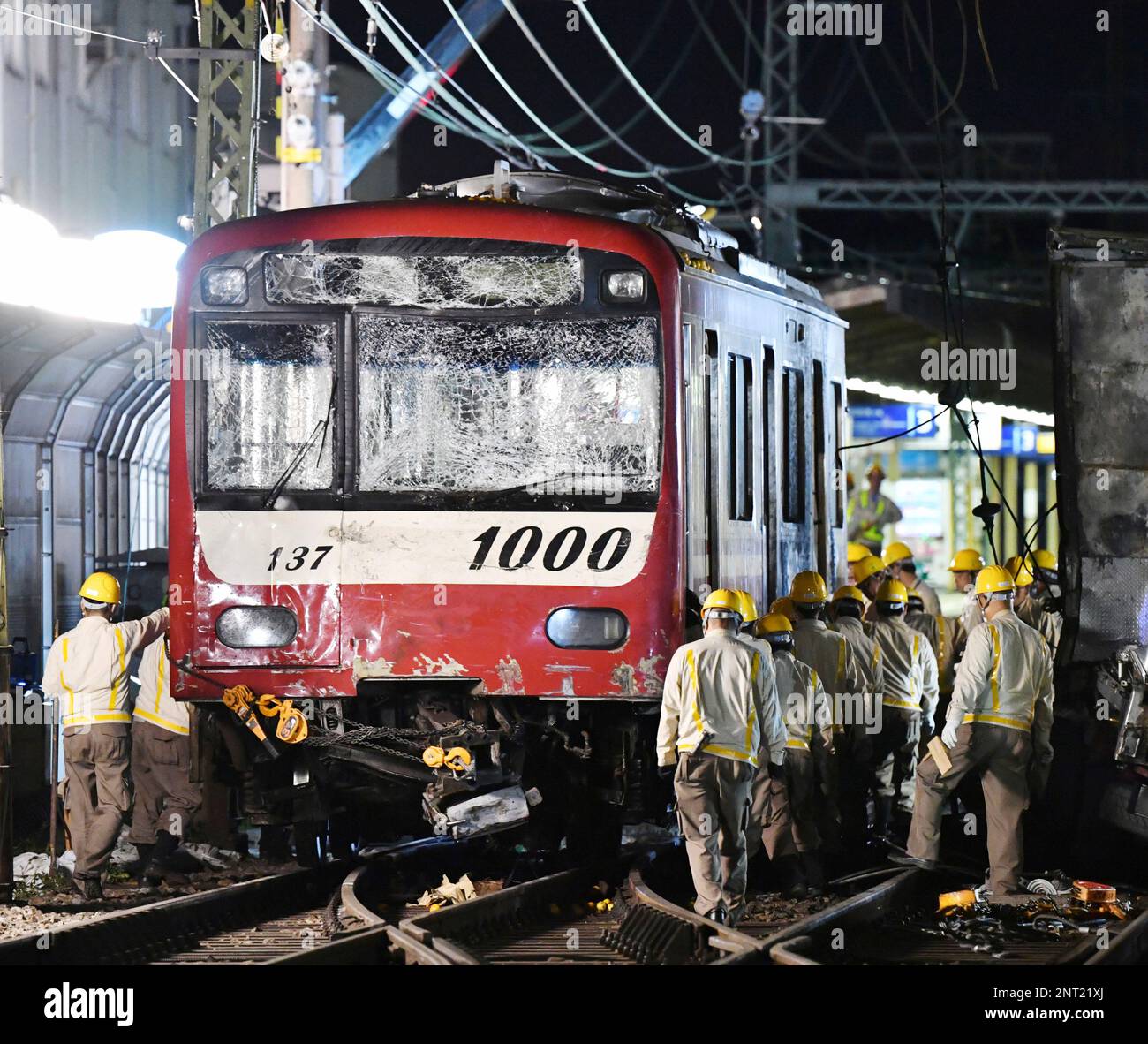 Workers push a train of KeikyuLine between Kanagawa Shinmachi Station ...