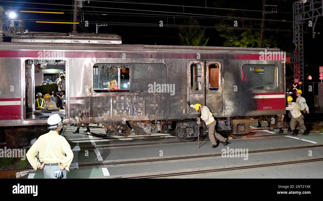 Workers push a train of KeikyuLine between Kanagawa Shinmachi Station ...