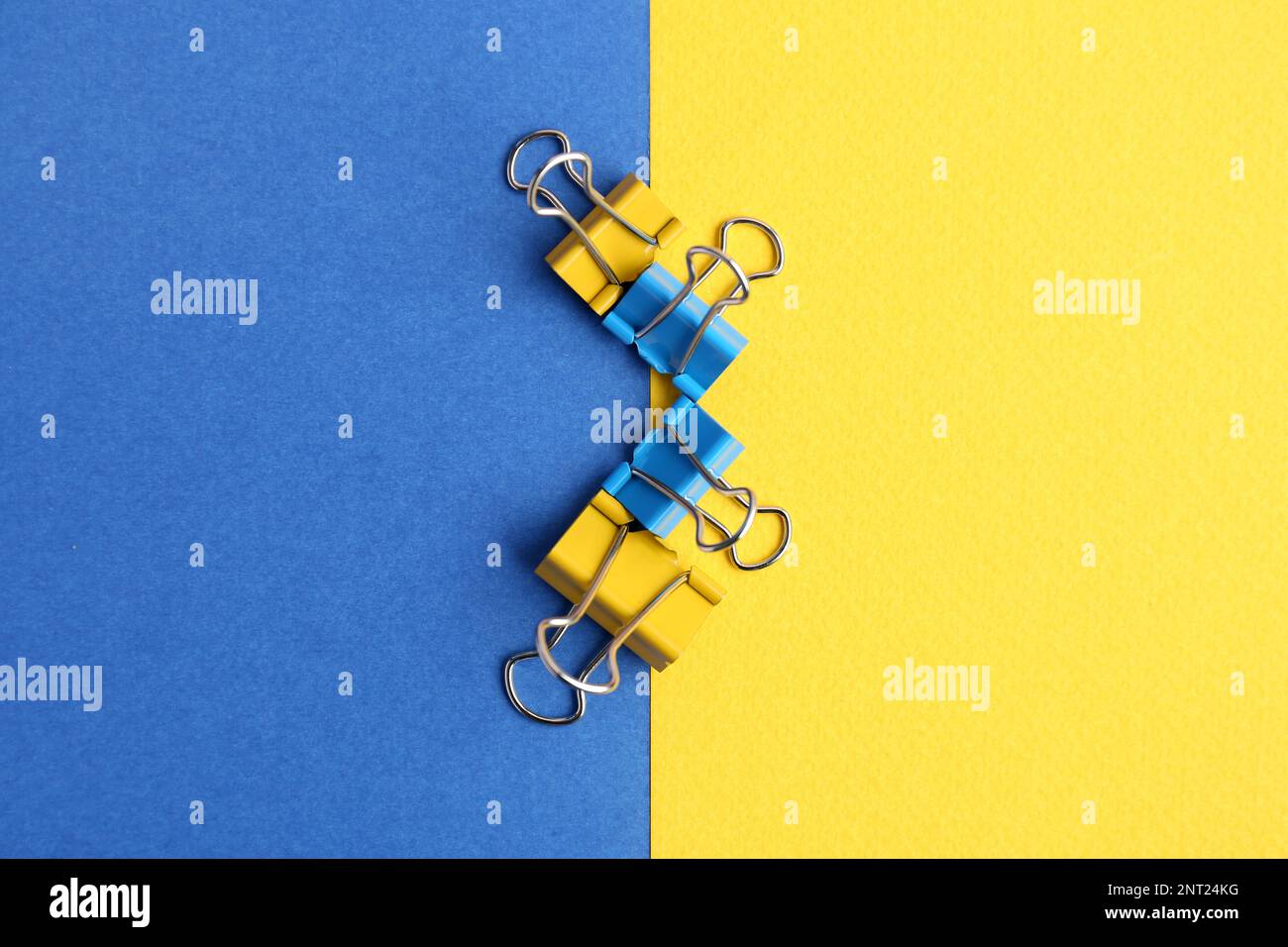 Blue and yellow binder clips on color background Stock Photo - Alamy
