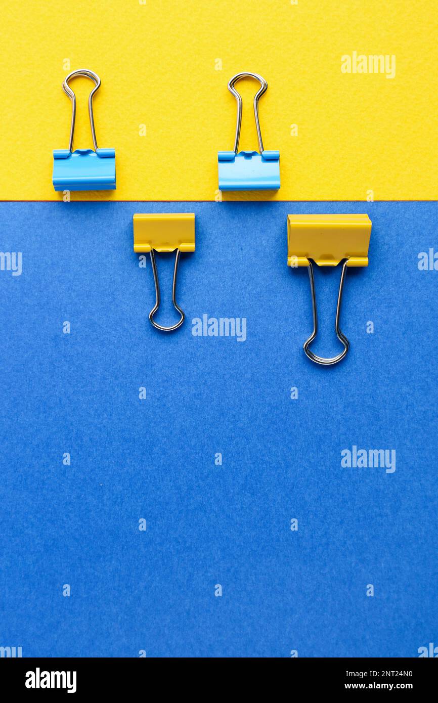 Blue and yellow binder clips on color background Stock Photo - Alamy