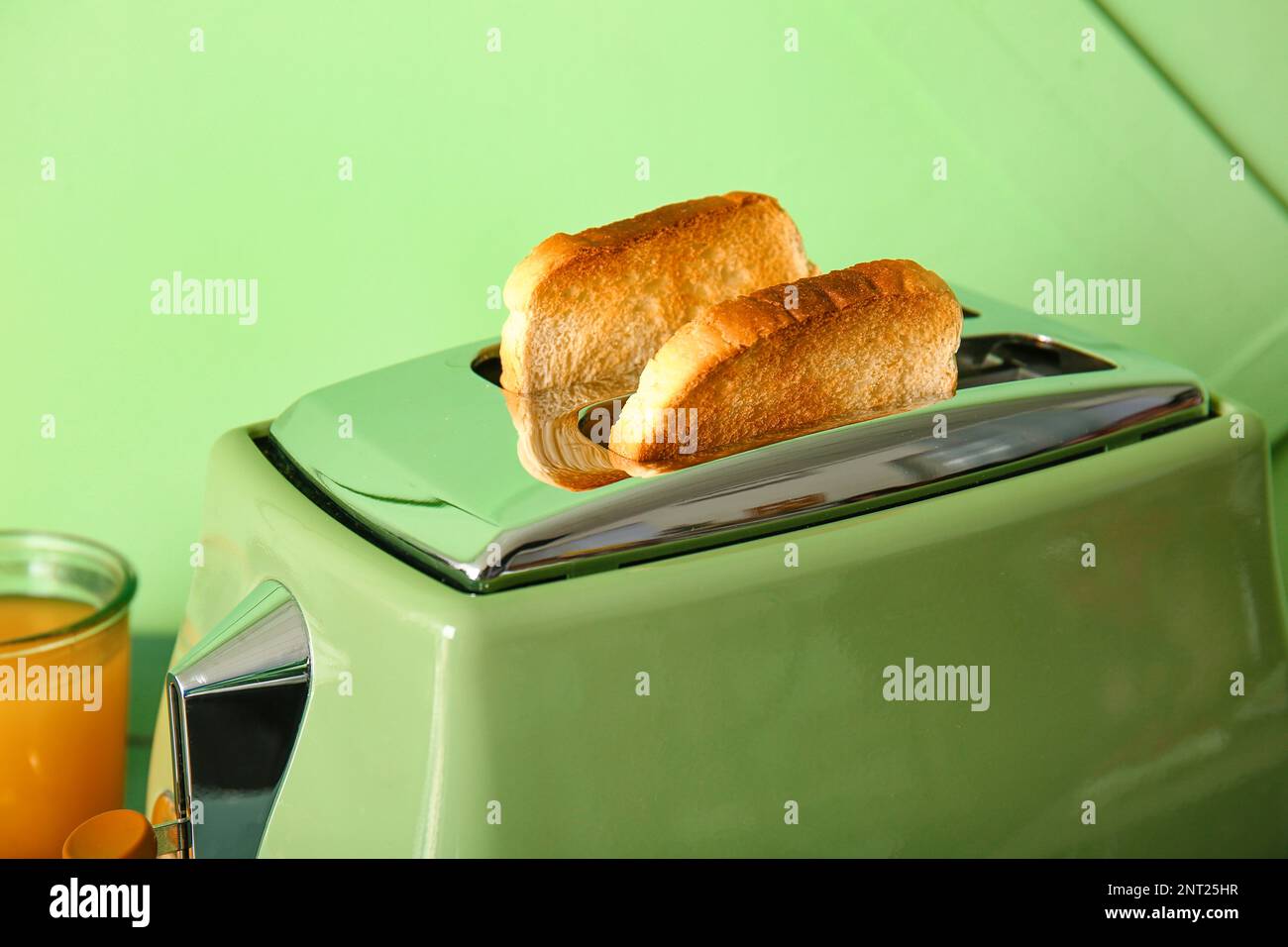 Crispy bread slices in modern toaster on green background, closeup Stock Photo - Alamy