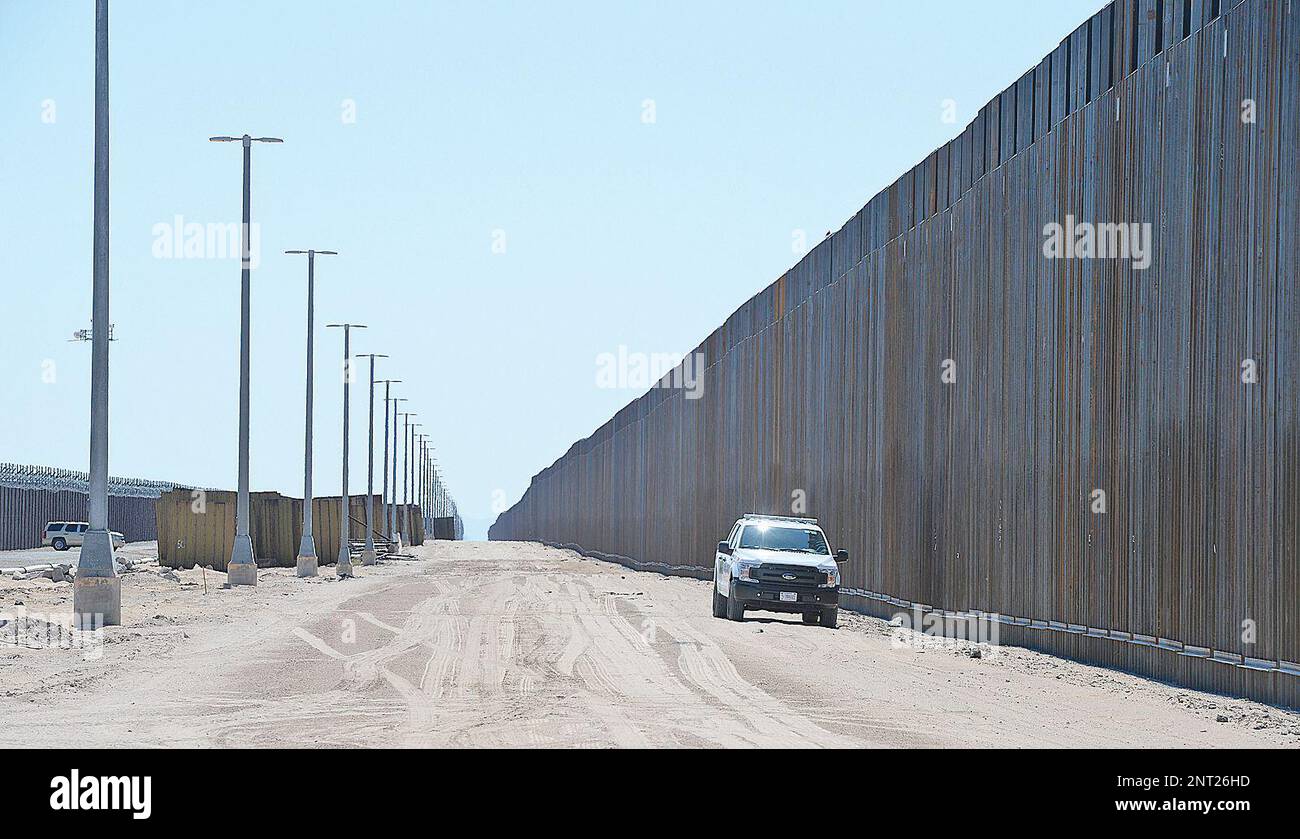 U.S. Border Patrol vehicles sit parked between the 30-foot high ...