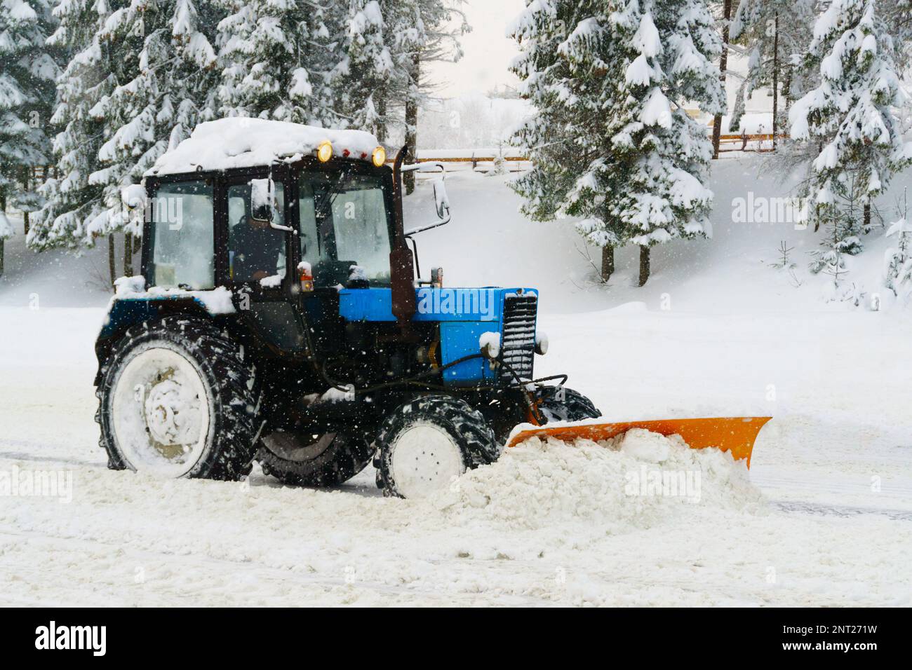 Blue snowblower grader clears snow covered ski resort road in mountains ...