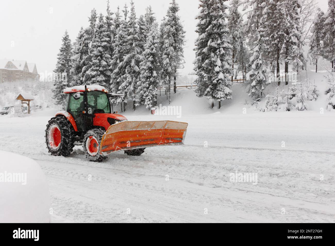 Red snowblower grader clears snow covered ski resort road in mountains ...
