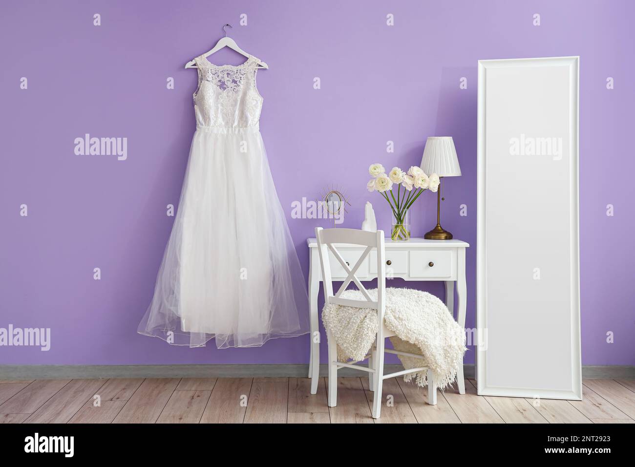 Interior of dressing room with flowers in vase, table and wedding dress ...