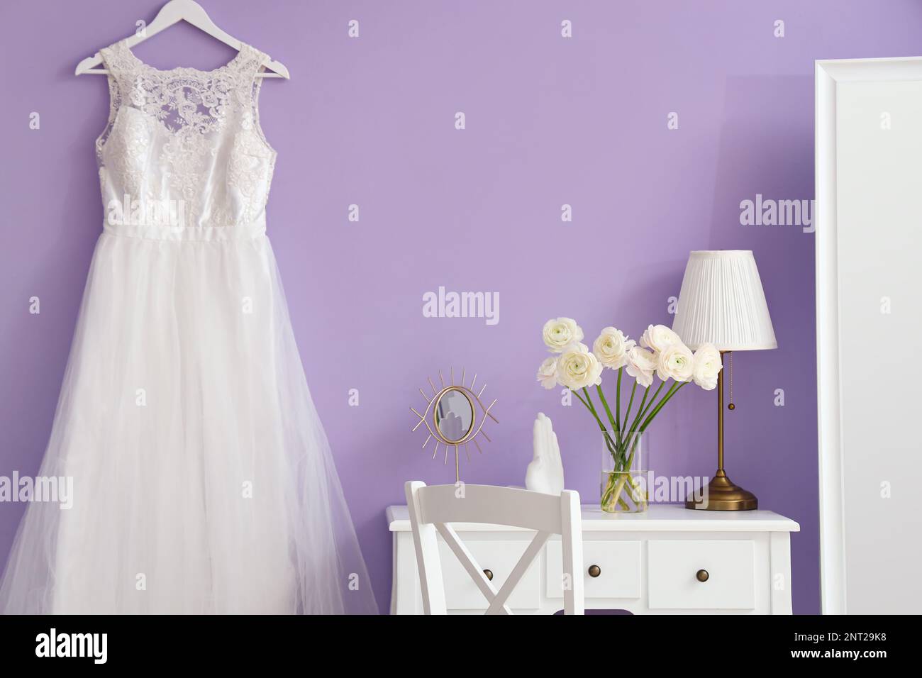 Interior of dressing room with flowers in vase, table and wedding dress ...