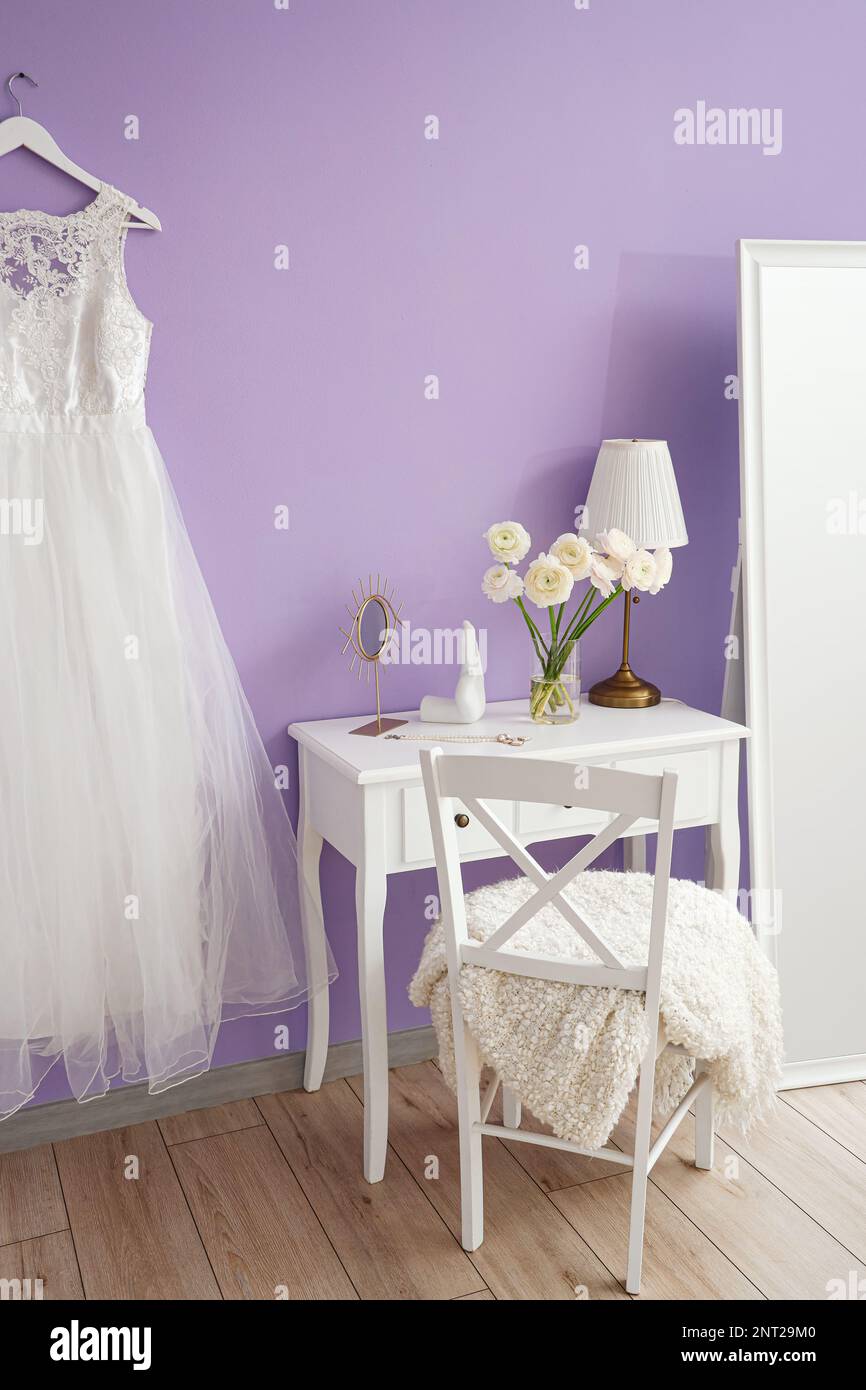 Interior of dressing room with flowers in vase, table and wedding dress ...