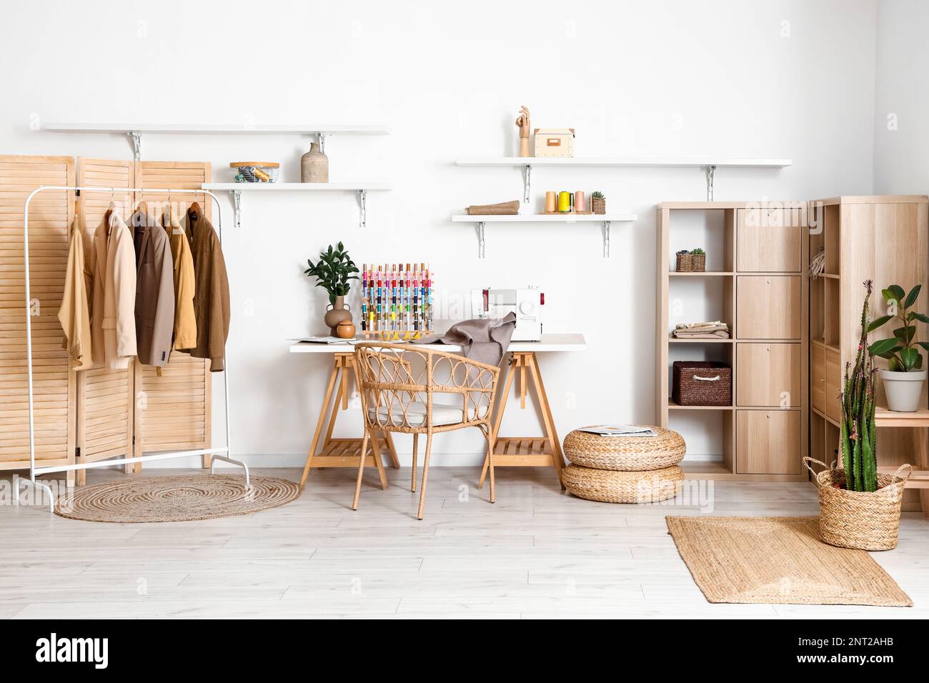 Interior of modern atelier with tailor's workplace, clothes and shelves ...