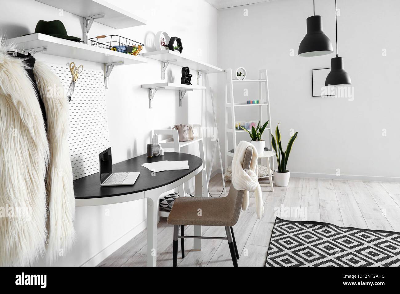 Interior of modern atelier with tailor's workplace, shelving units and ...