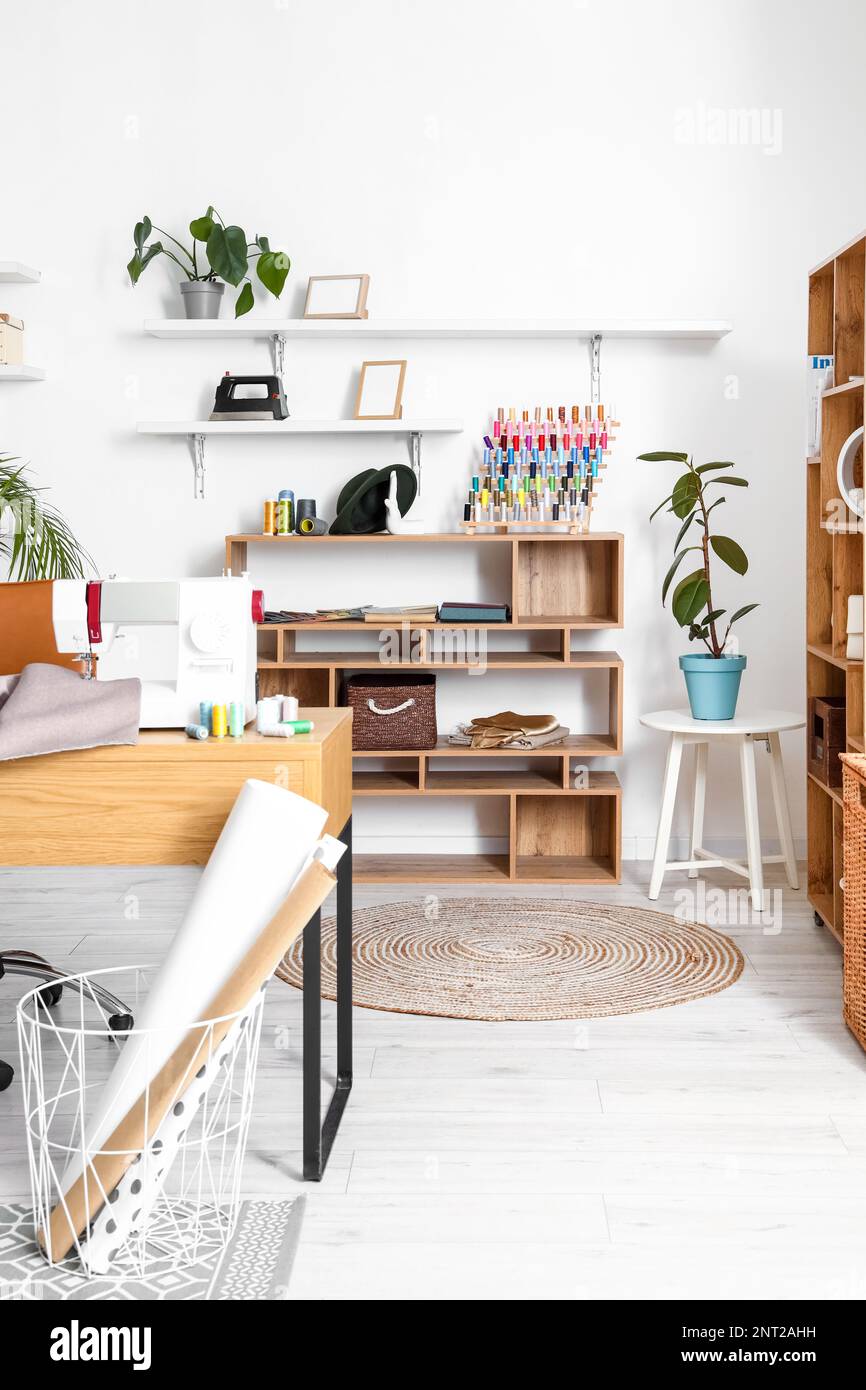 Interior of modern atelier with tailor's workplace and shelving units ...