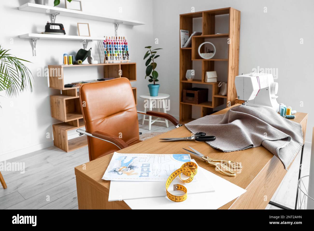 Interior of modern atelier with tailor's workplace and shelving units ...