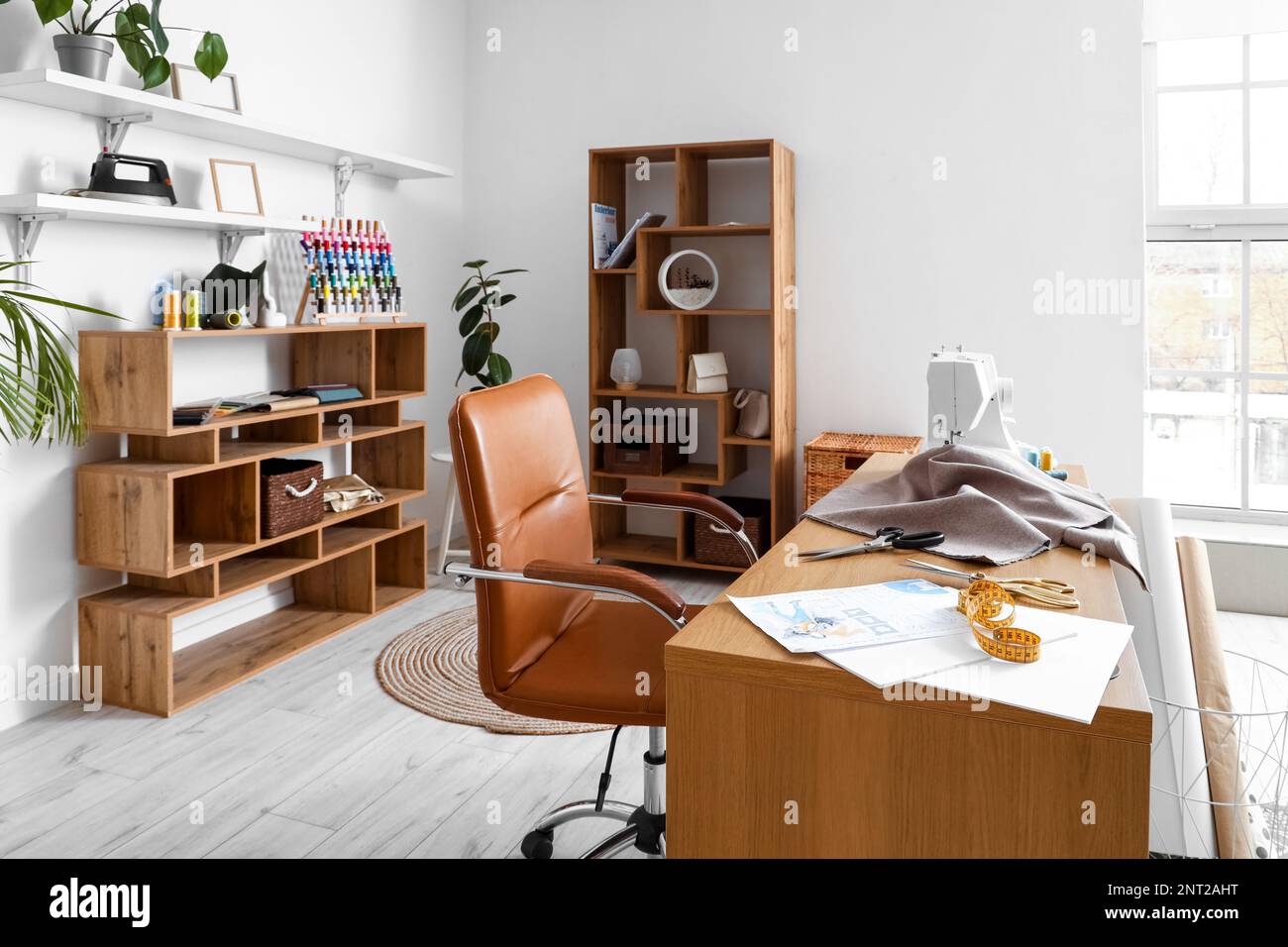 Interior of modern atelier with tailor's workplace and shelving units ...