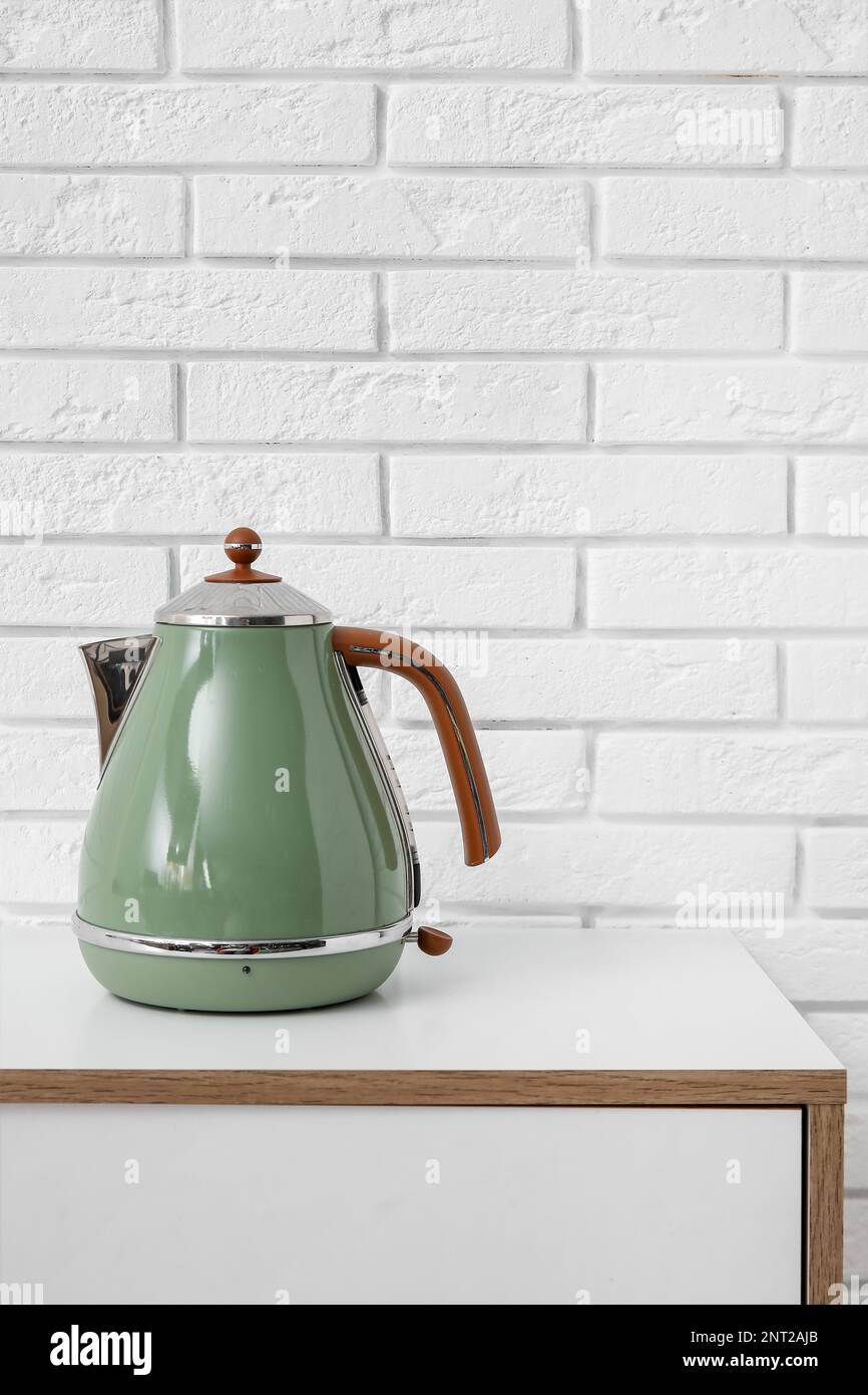 Electric kettle on table near white brick wall Stock Photo - Alamy