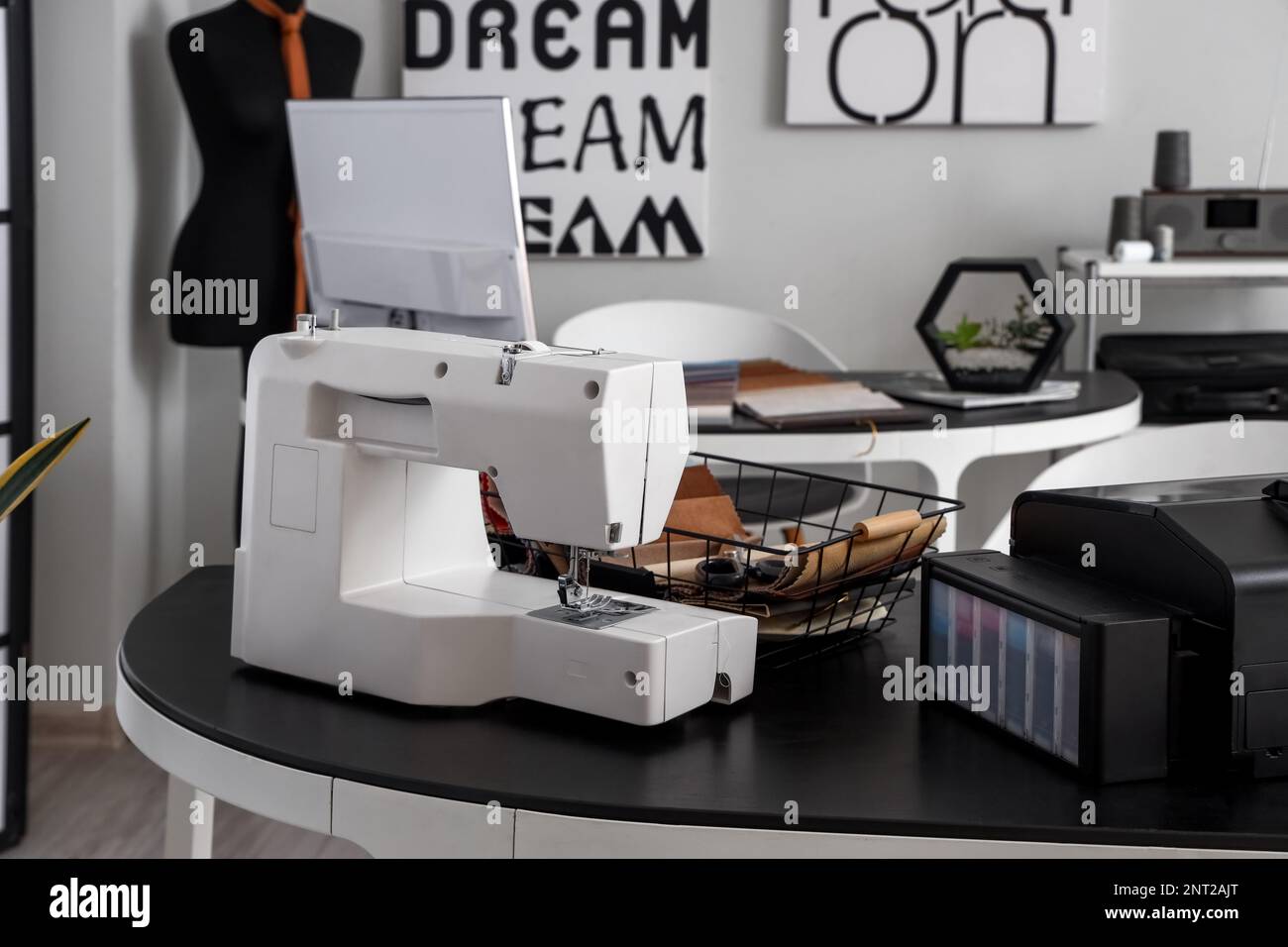 Tailor's workplace with sewing machine and fabric samples in atelier ...