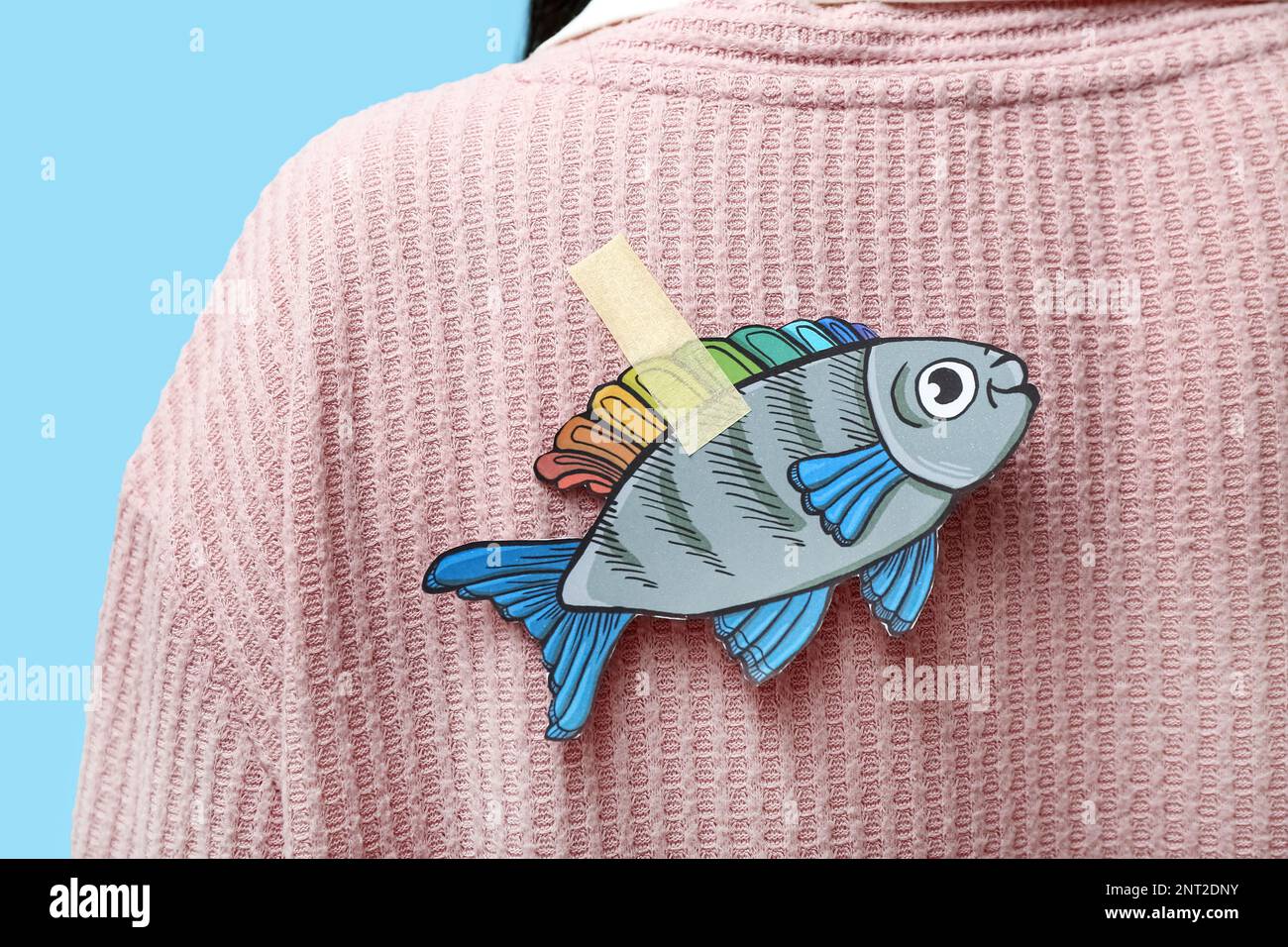 Paper fish on woman's back against blue background, closeup. April ...