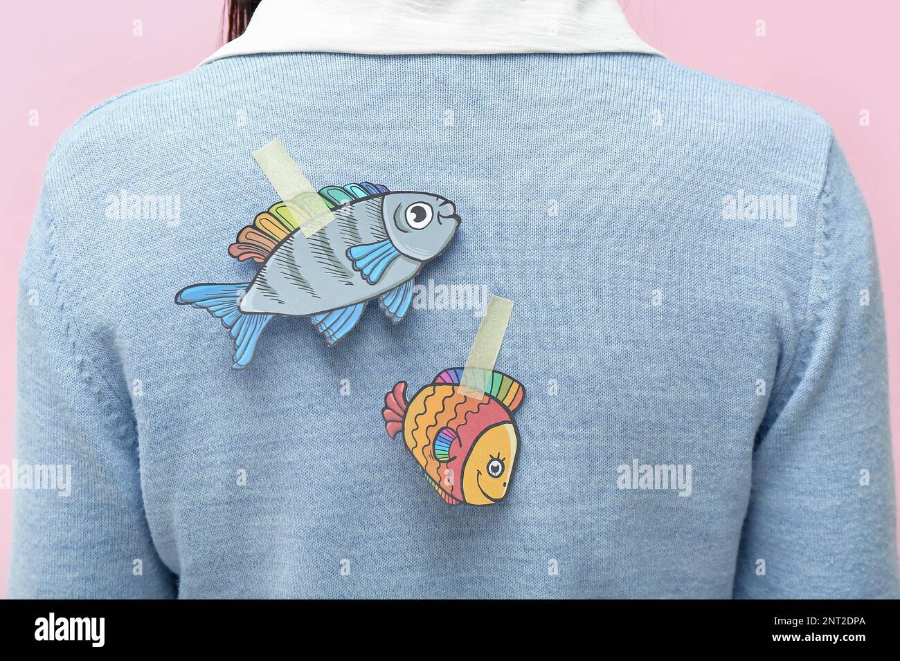 Paper fishes on woman's back against pink background, closeup. April ...