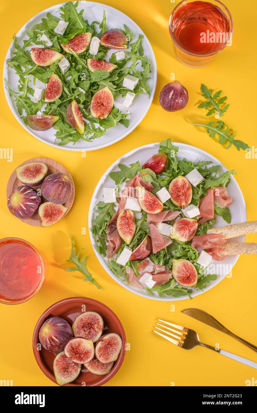 Autumn figs salad with arugula, feta, raw ham in two white plate on ...