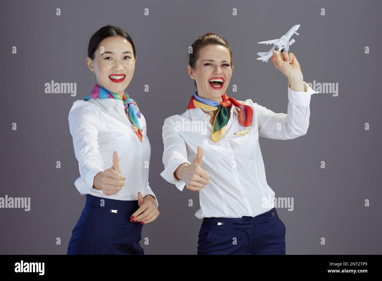happy stylish female air hostesses in blue skirt, white shirt and scarf ...