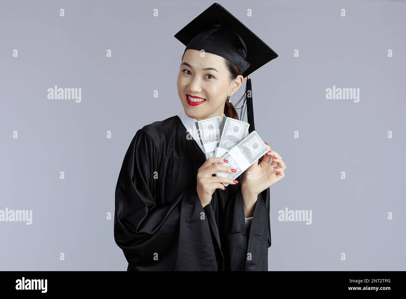 happy modern graduate student asian woman with money isolated on gray ...