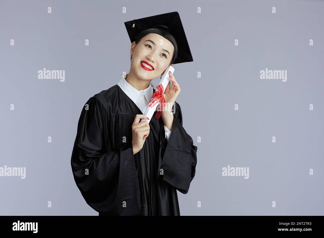 happy modern graduate student asian woman with diploma against grey ...
