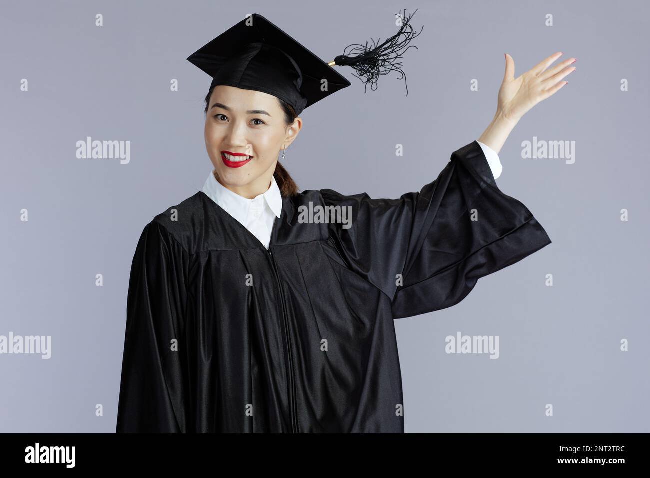 cheerful modern graduate student asian woman in graduation gown with ...