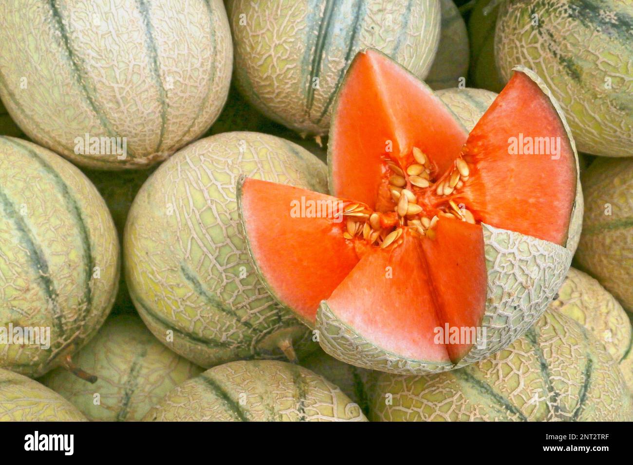 Full frame close-up on a stack of melons with one cut in half on a ...