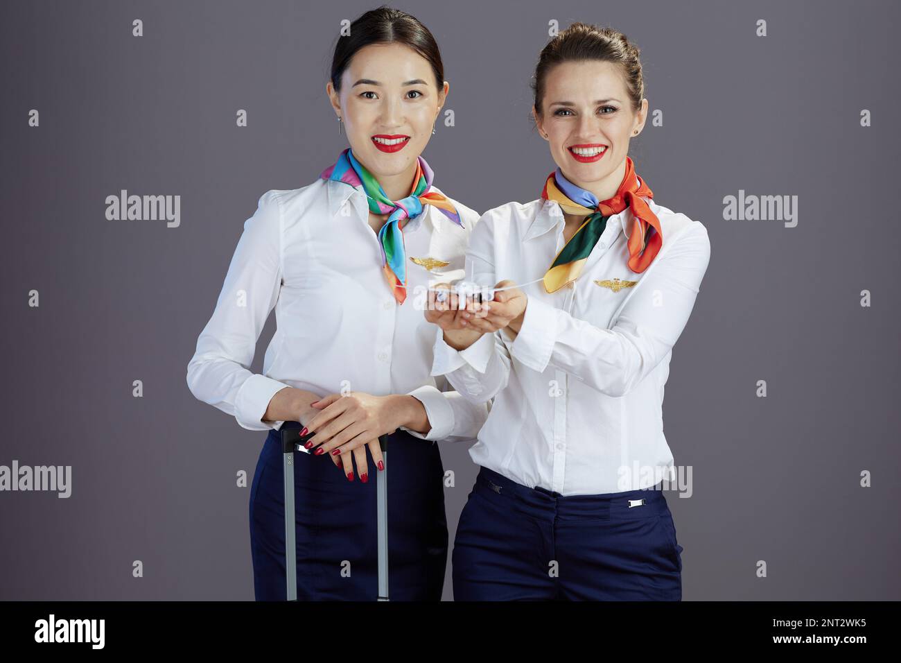 smiling stylish female stewardesses in blue skirt, white shirt and ...