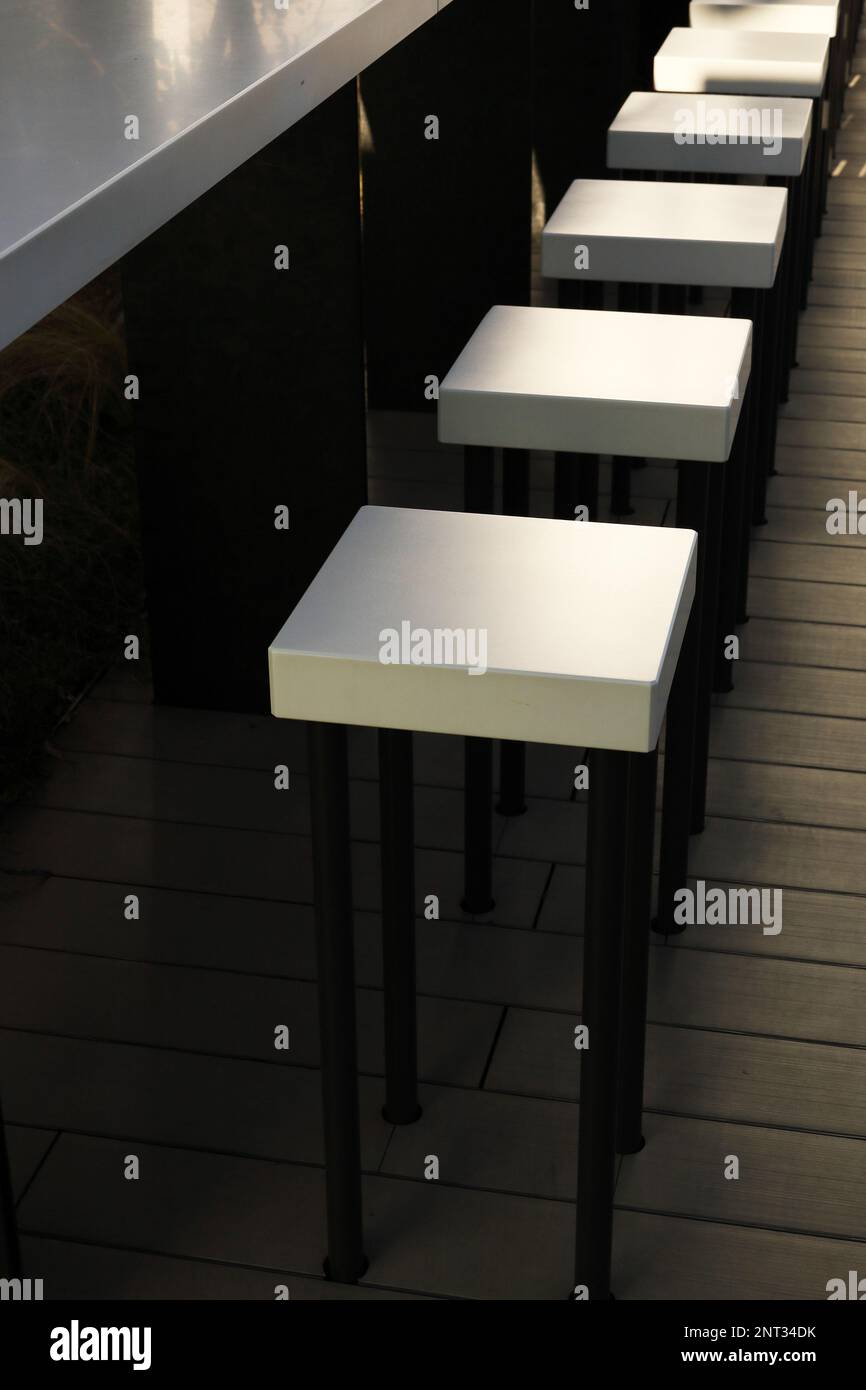 White modern counter stools lined up on the wooden deck Stock Photo - Alamy