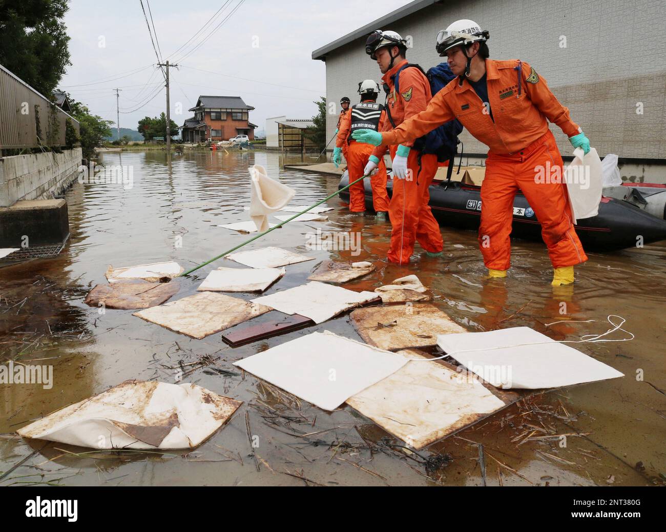 Firefighters work to absorb oil in Omachi Town where the flood occurred ...