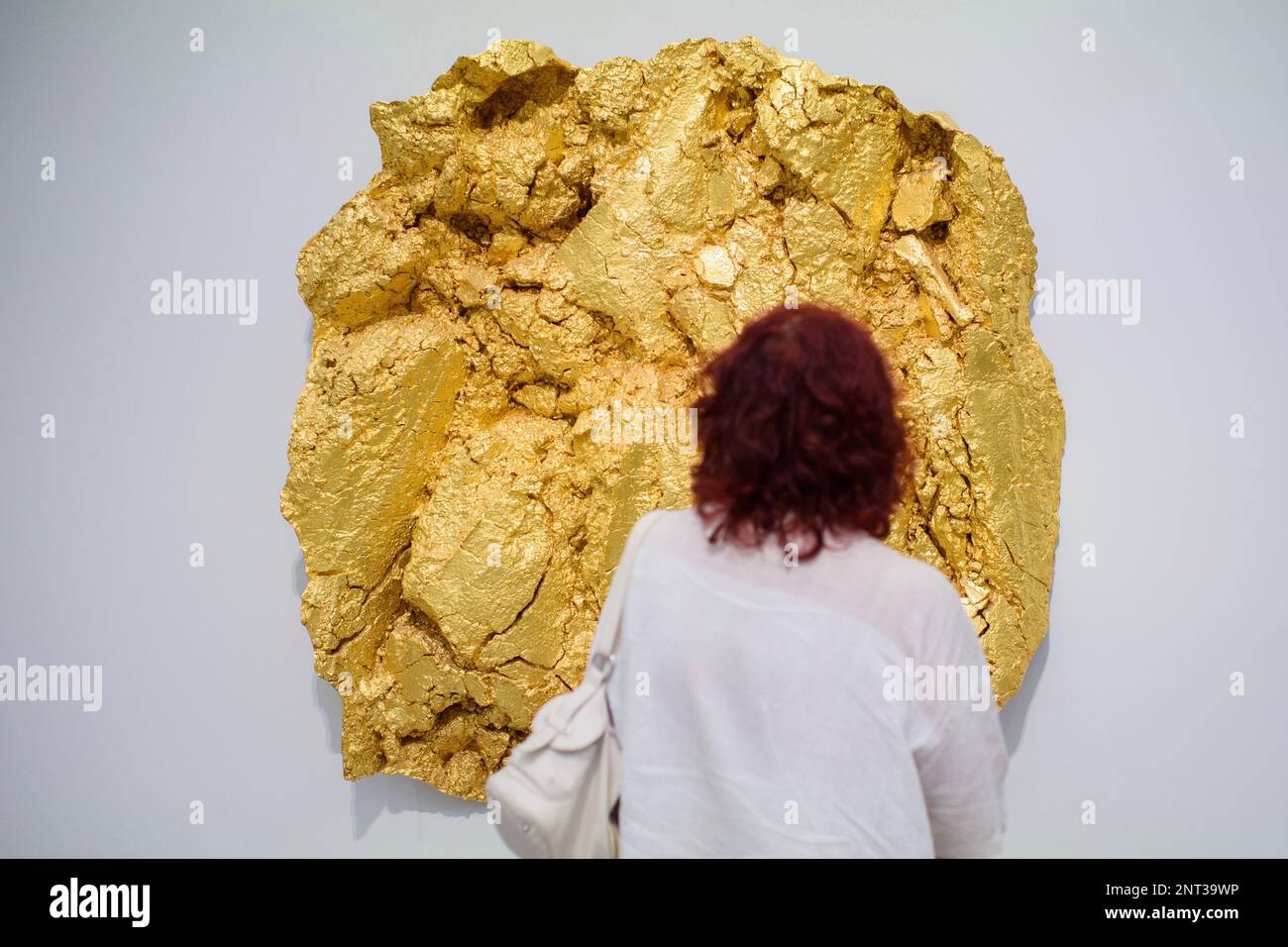 A visitor watches a golden plaster stone artwork called 'Acker' of ...
