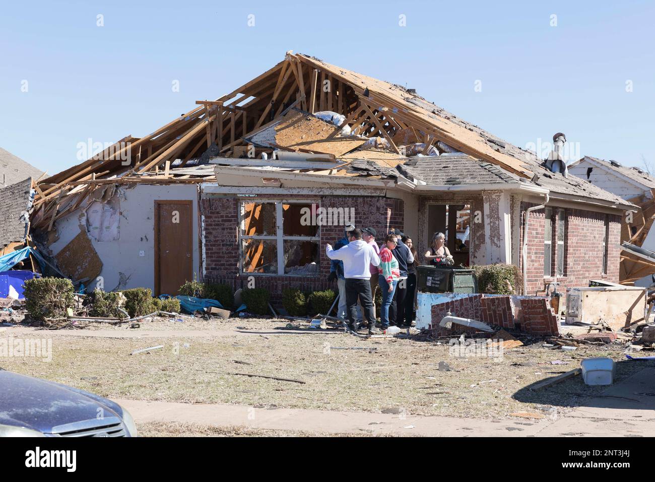 A family gathers in front of their damaged home on Conway Drive on ...